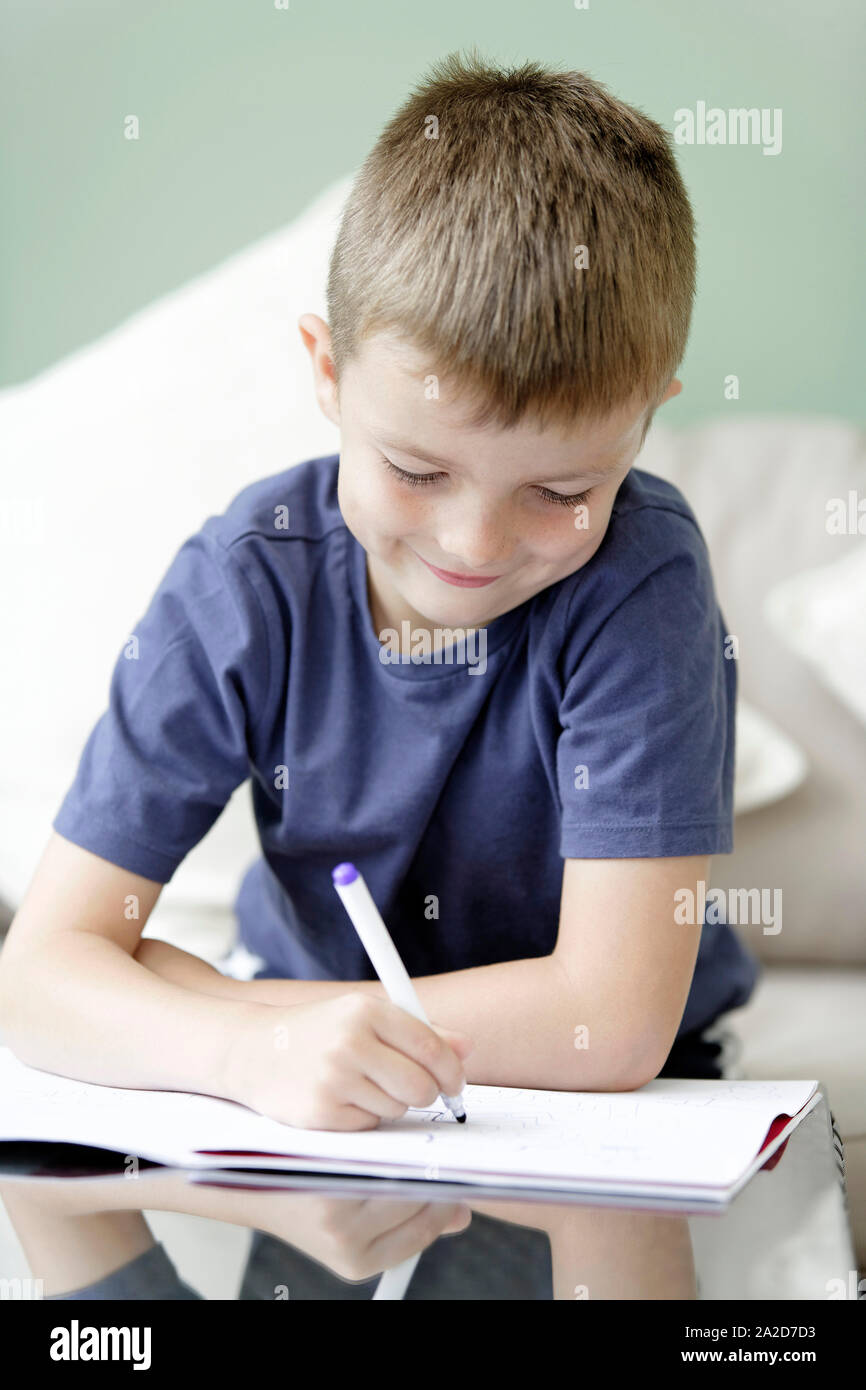 Young boy drawing and writing on a pad doing his homework Stock Photo ...