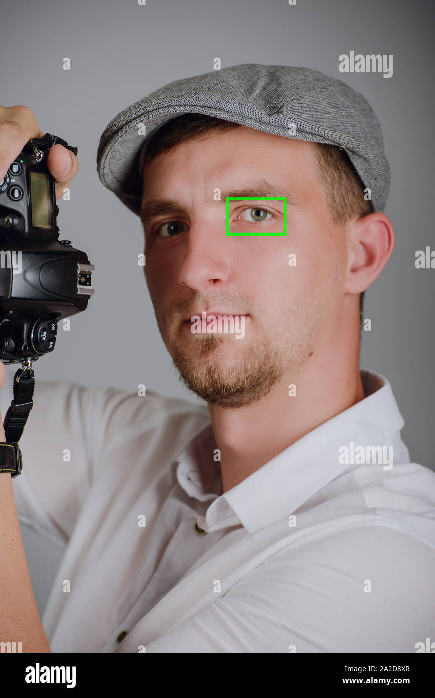 Young man using a professional camera in studio. Green box square frame ...