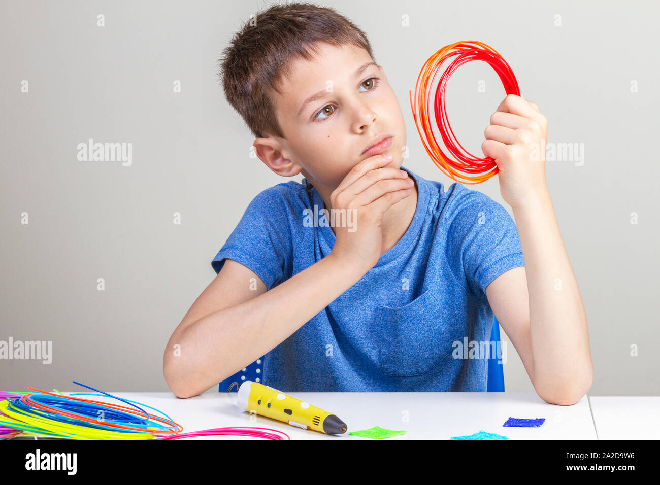Kid holding 3d pen and colorful filaments for 3 d pen and thinking what ...