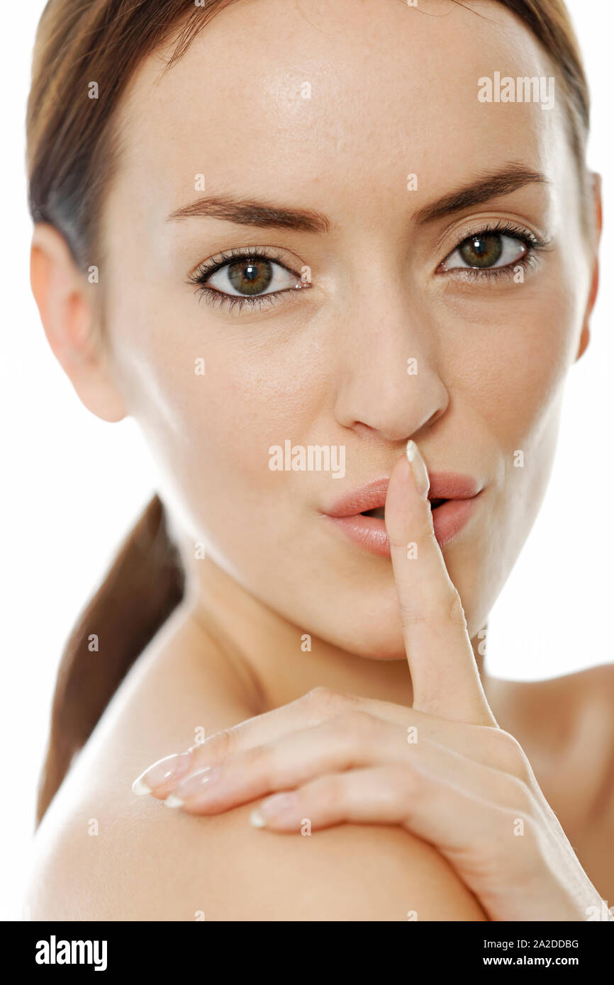 Attractive woman holding her finger over her lips expressing silence ...