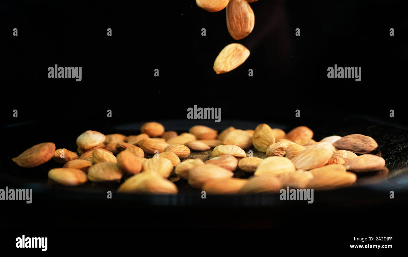 Almond and apricot grains, on the varnished plate falling seeds. The ...