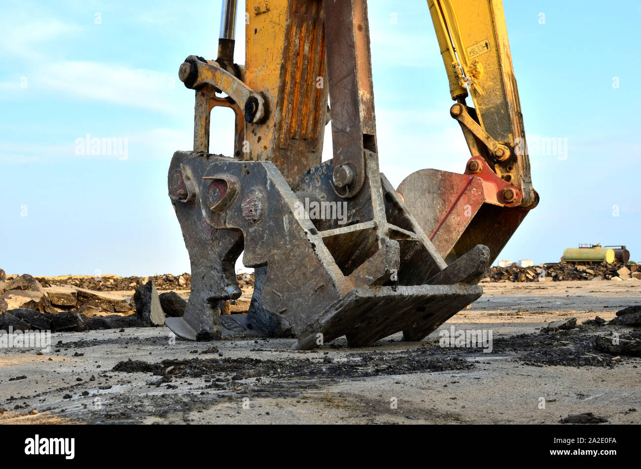 Excavator with hydraulic shears breaks asphalt on a construction site ...