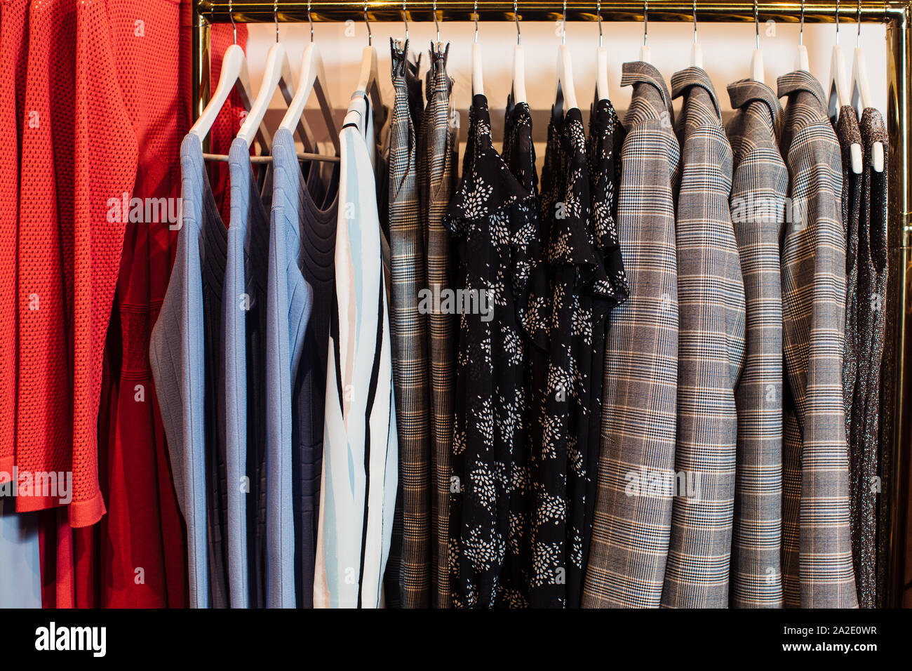 Close-up view of various stylish clothes hanging on hangers in boutique ...