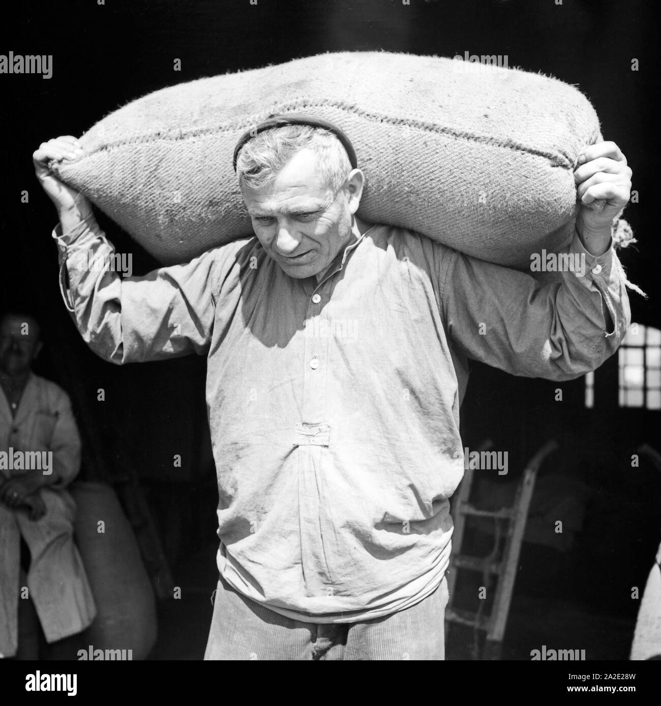 Deutschland 1930er jahre warehouseman carrying sack out iof warehouse ...