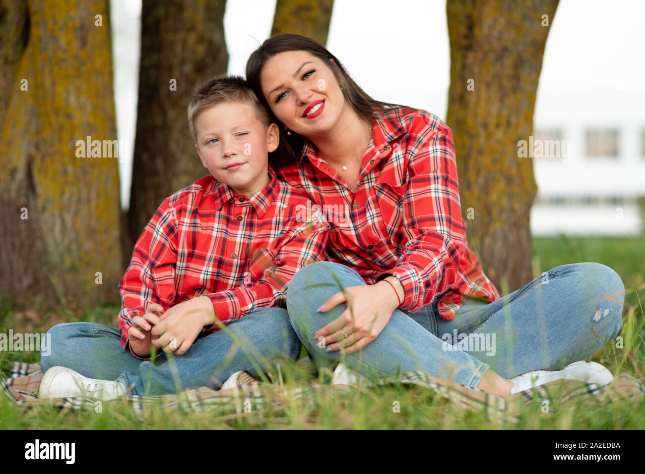 Mom And Son Sitting On The Bedspread In Lotus Position Hugging Stock