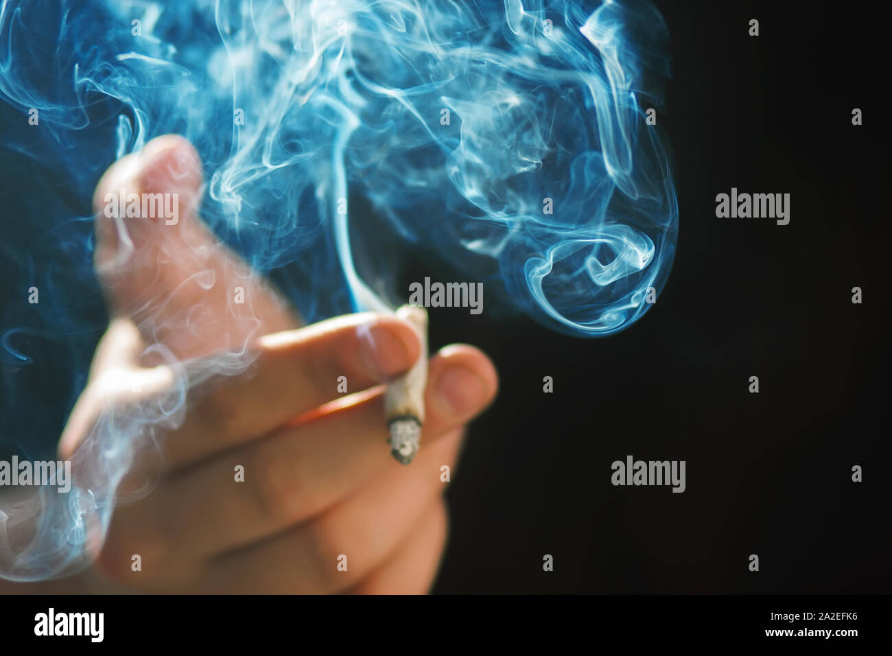 The cigarette in his hand smoulders and emits a thick blue toxic smoke ...