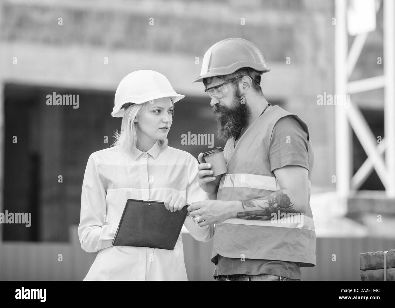 Woman engineer and builder communicate construction site. Discuss ...