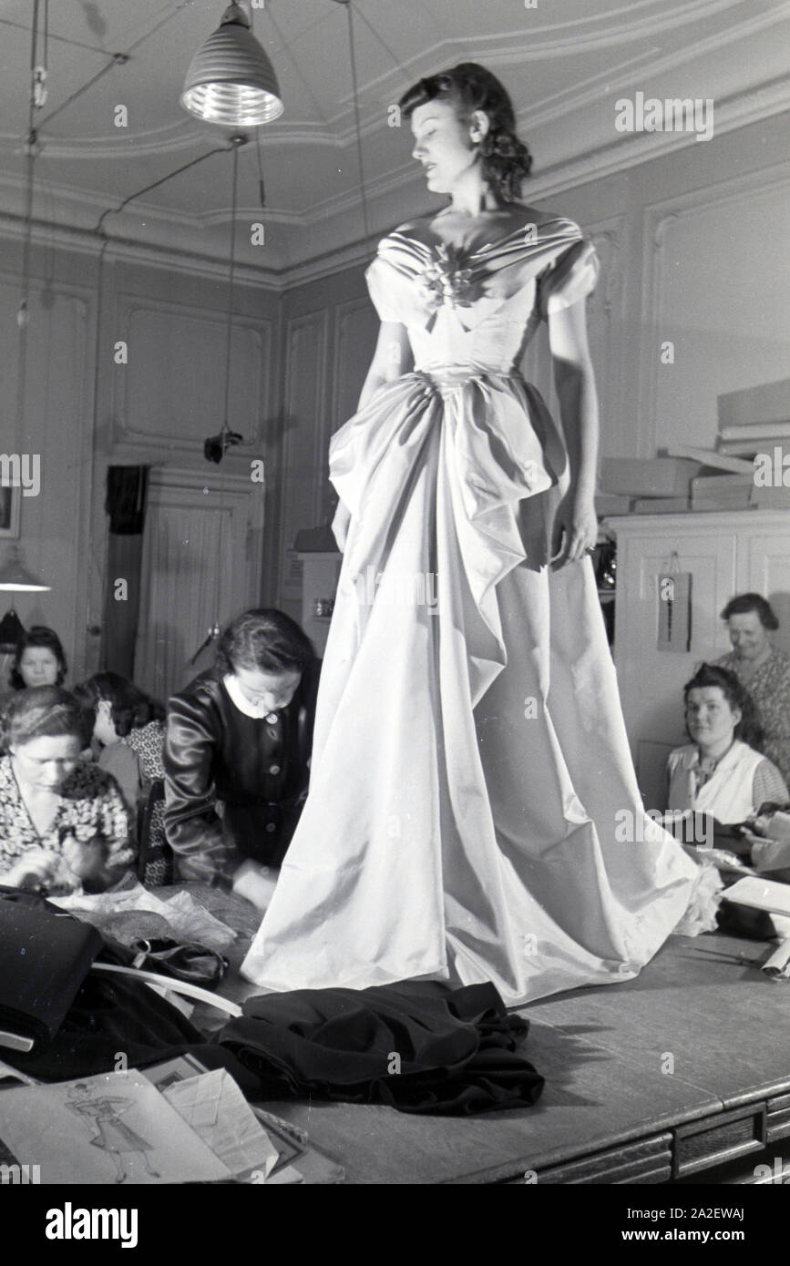 Ein Model und Schneiderinnen bei der Anprobe eines Kleides von Modesch ...