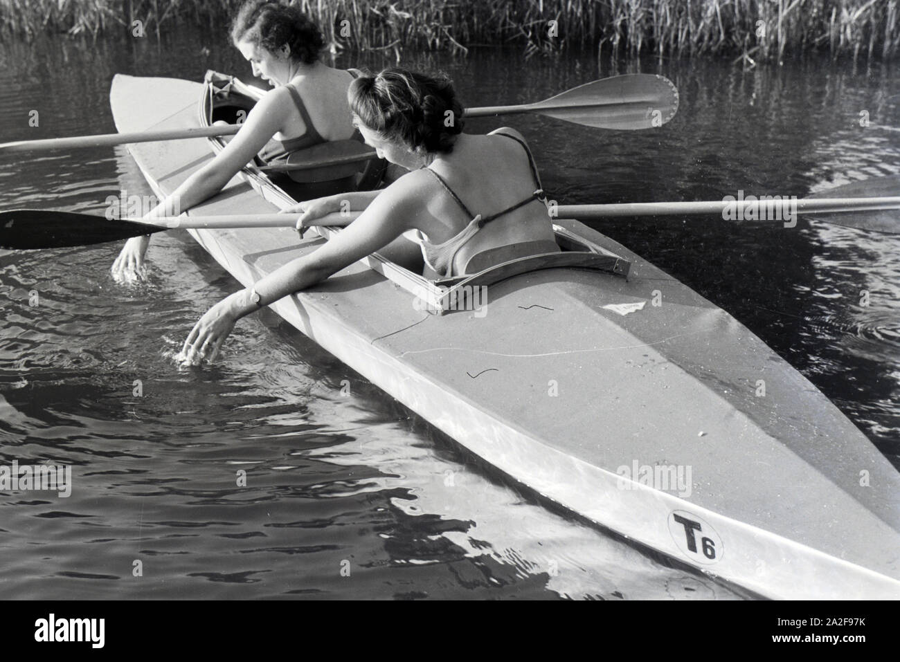 Zwei junge Frauen in Badeanzügen paddeln in einem Boot / Klepper T6 auf ...