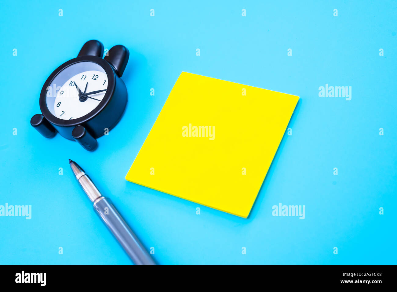 Flat lay of an alarm clock, pen and yellow paper to write any text ...