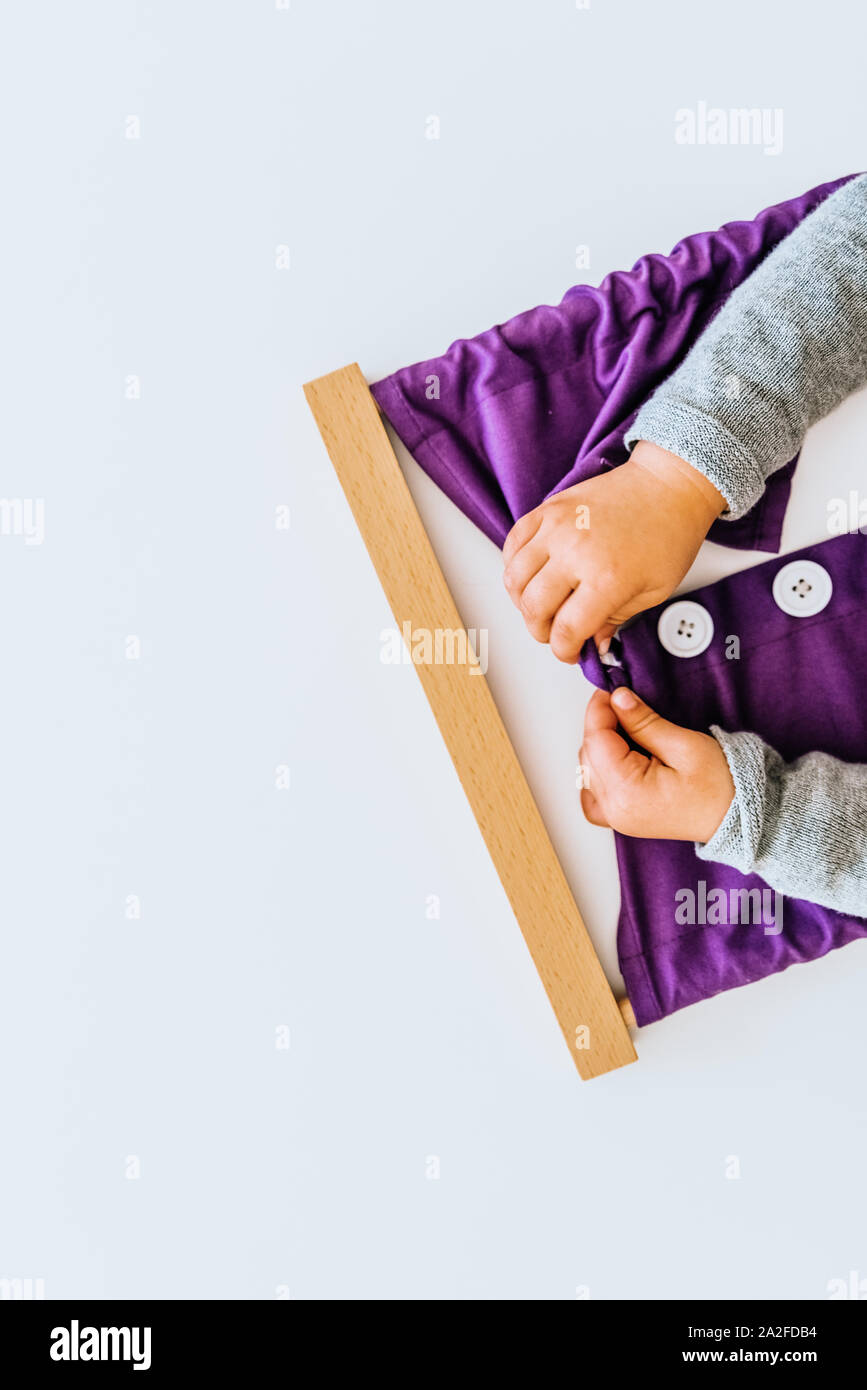 Girl buttoning a montessori frame to develop the dexterity of her ...