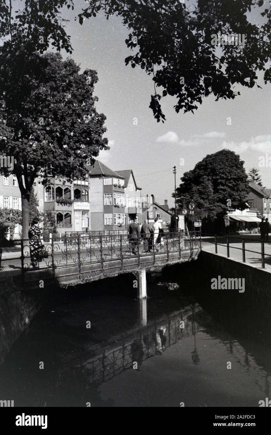 Passanten spazieren eine Straße mit Wohnhäusern entlang, die direkt am ...