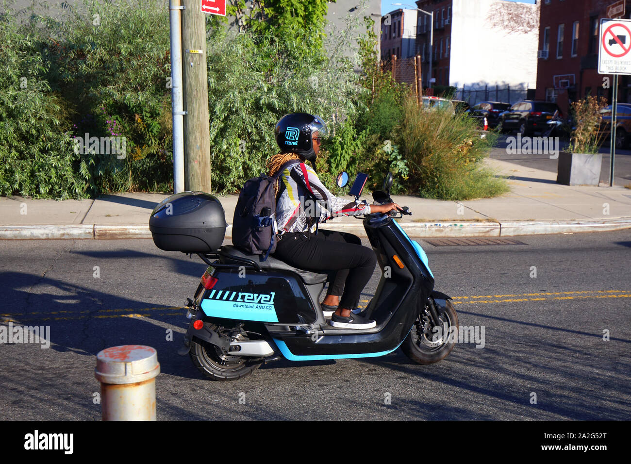 A woman on a rental electric moped from app-based Revel Transit Stock ...
