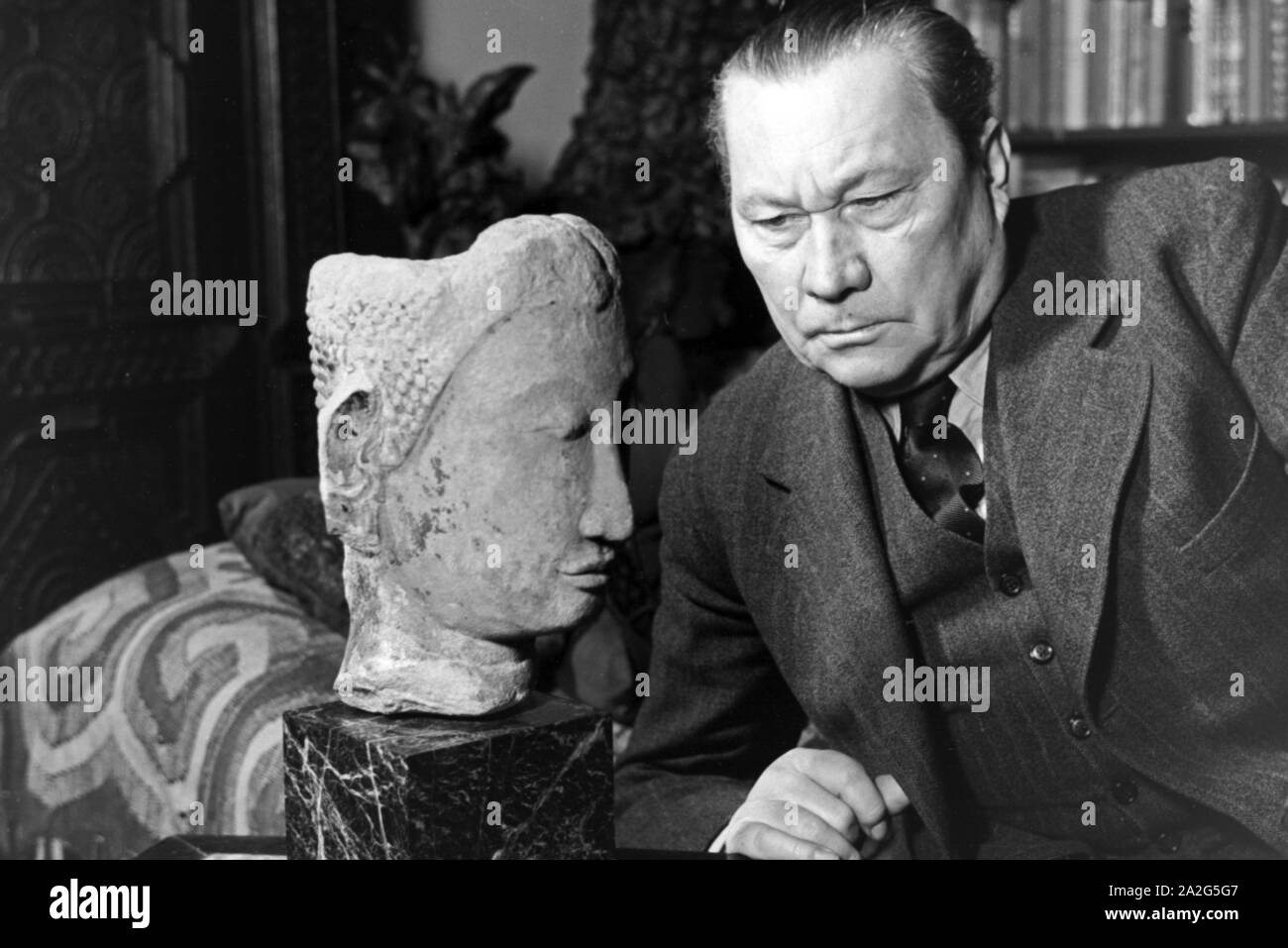 Der deutsche Schauspieler Paul Wegener mit dem Kopf einer Buddhastatue ...