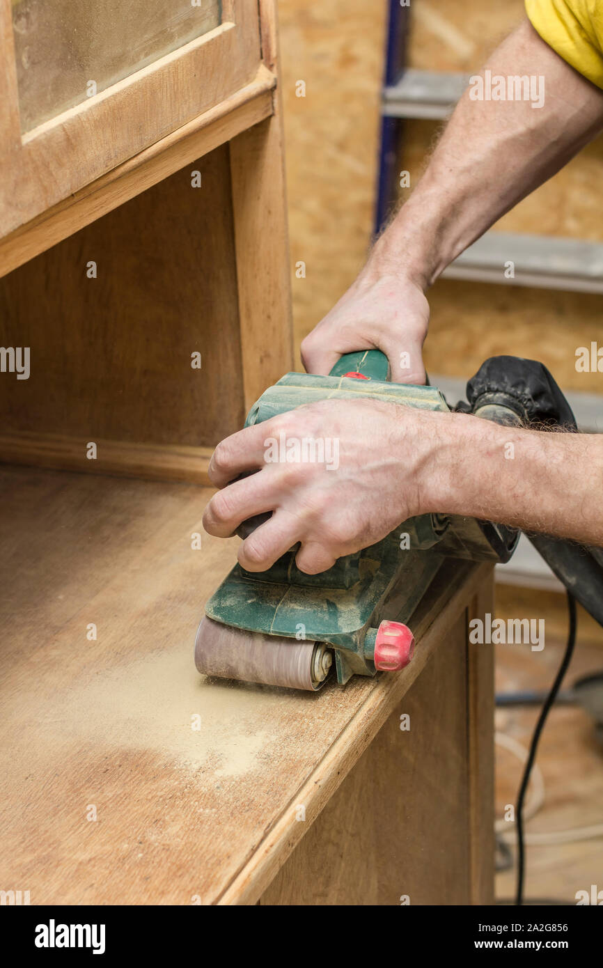 Carpenter restores vintage the wooden a sideboard by an electric of the ...