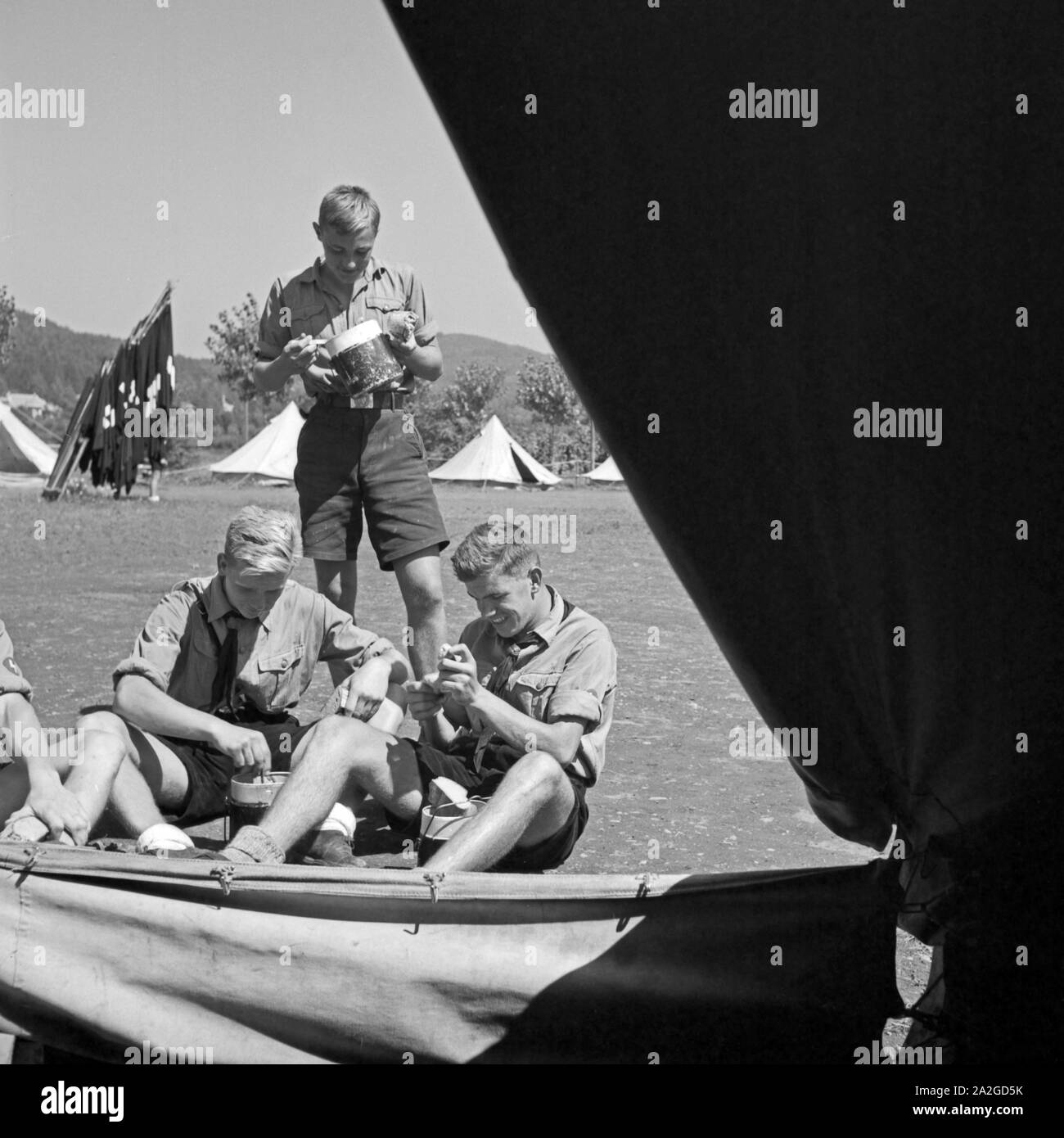 Hitlerjungen sitzen in der Mittagspause zusammen beim feldmäßigen Essen ...