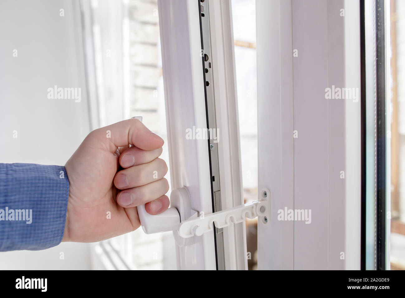 The hand holds the handle of opened window with safe restrictor lock ...