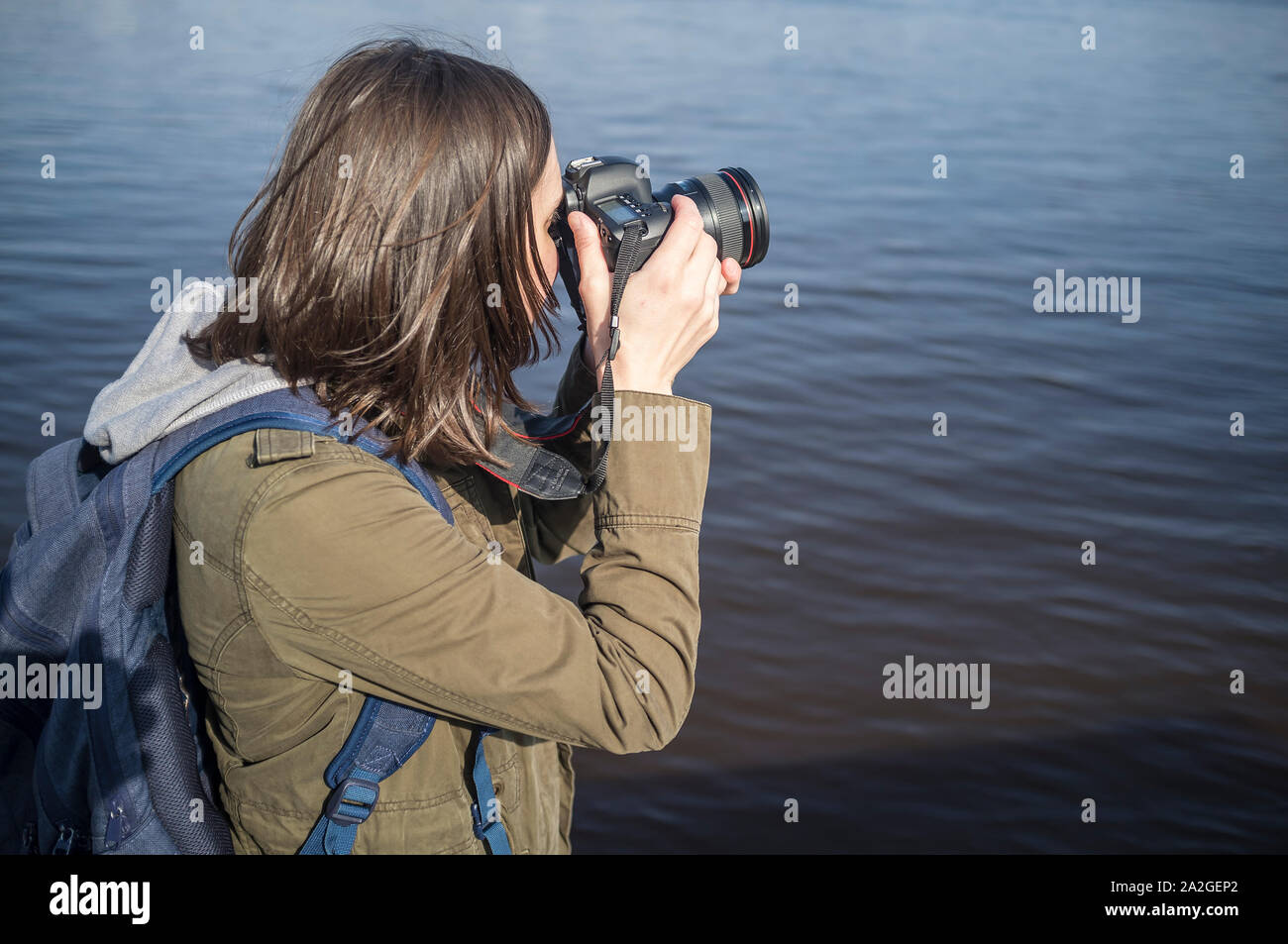 Cute female photographer with camera in hands on background of river ...