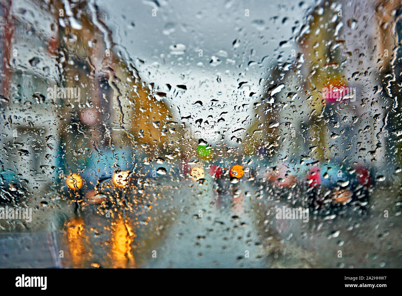 Car windshield with rain drops during storm and blurred stoplights ...