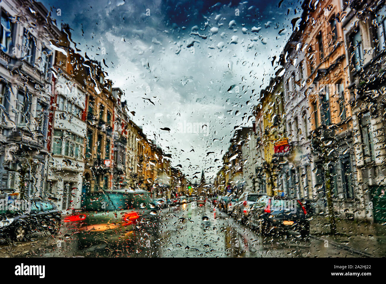 Car windshield with rain drops during storm and blurred stoplights ...