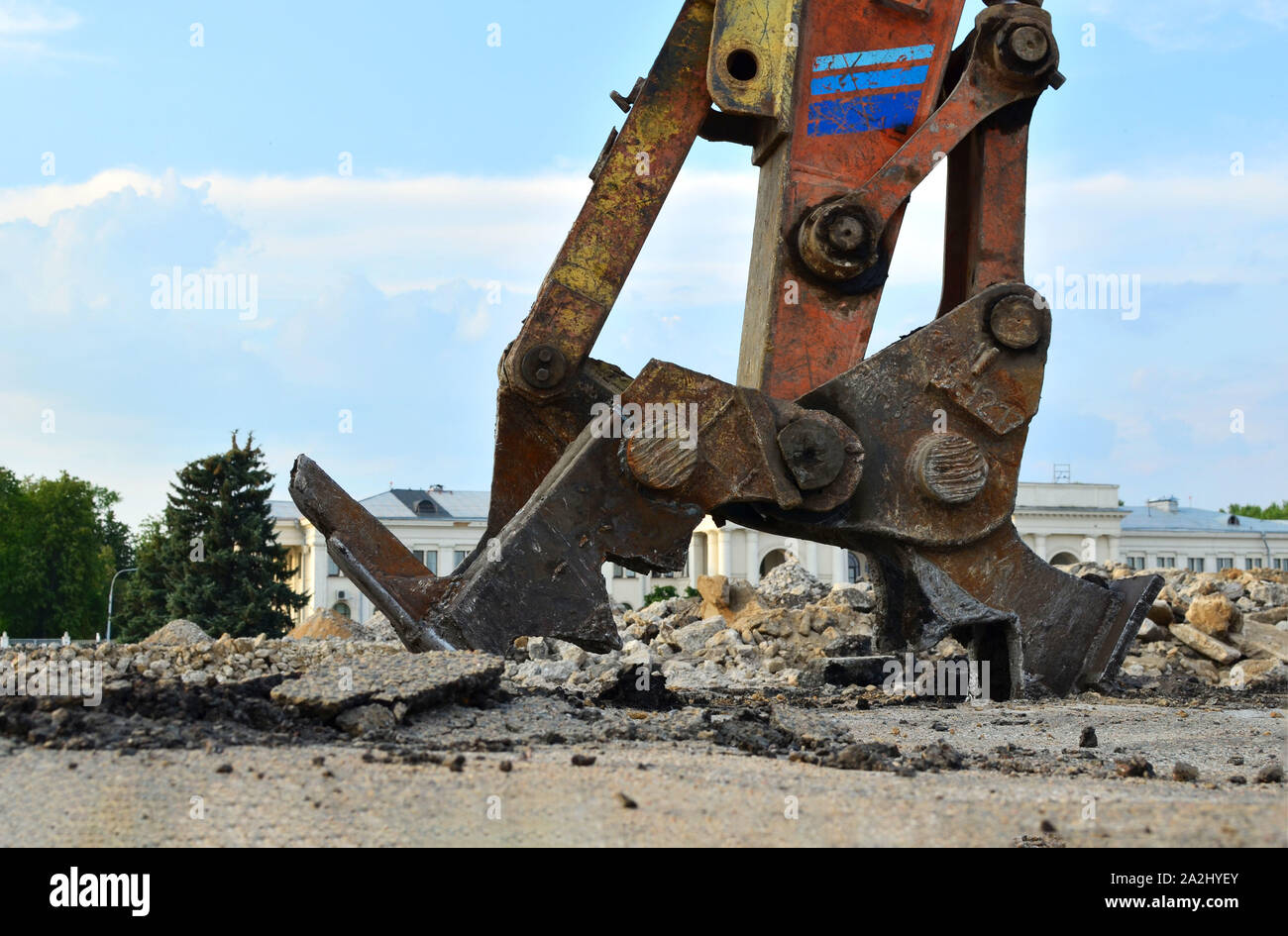 Excavator with hydraulic shears breaks asphalt on a construction site ...