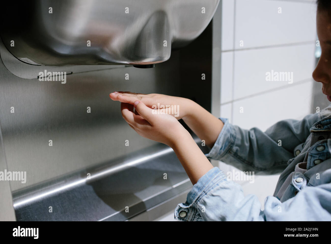 Kid air drying her hands on a public restroom Stock Photo - Alamy