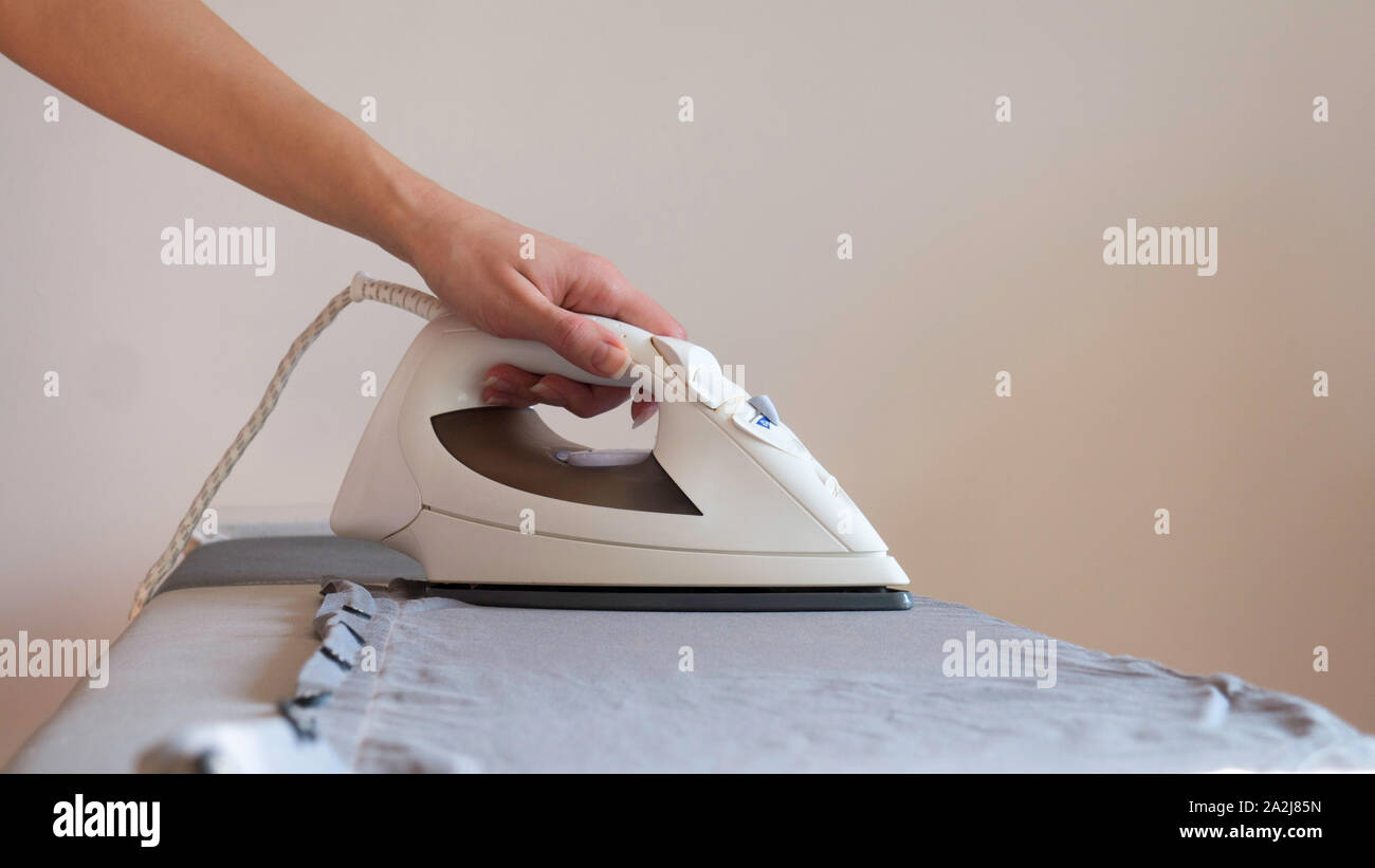 Close-up Of Woman's Hand Ironing Clothes On Ironing Board Stock Photo ...