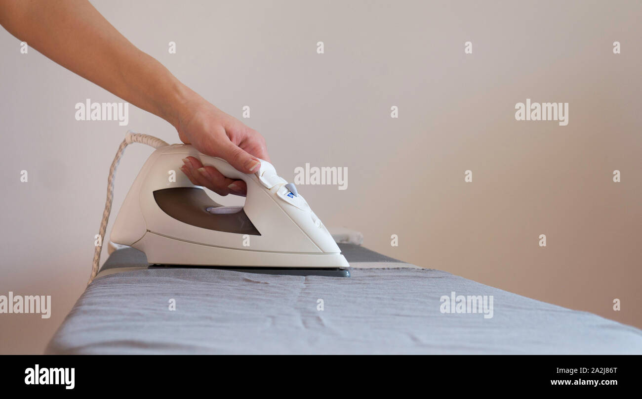 A hand holding modern electrical white iron ready to iron Stock Photo ...