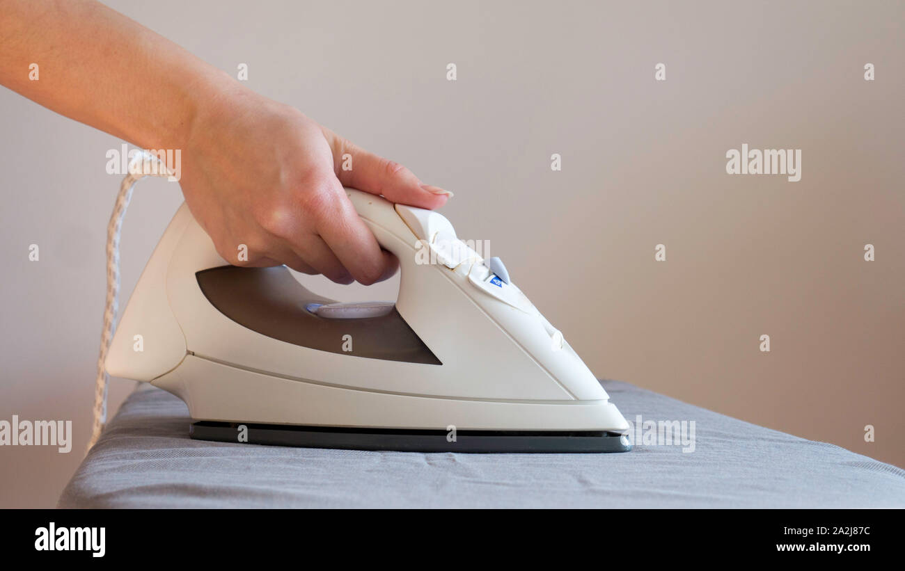 Woman hand holding a modern electrical white iron Stock Photo - Alamy