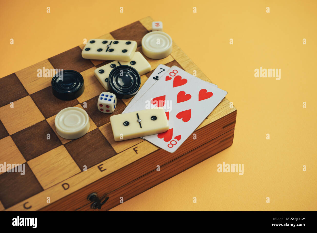 Various board games chess board, playing cards, dominoes on a orange ...