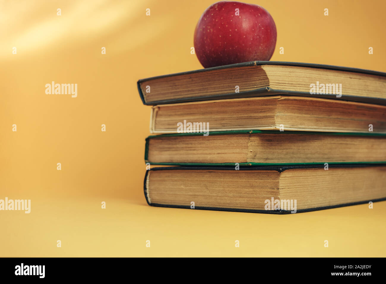 Beautiful books and red apple on a orange background Stock Photo - Alamy
