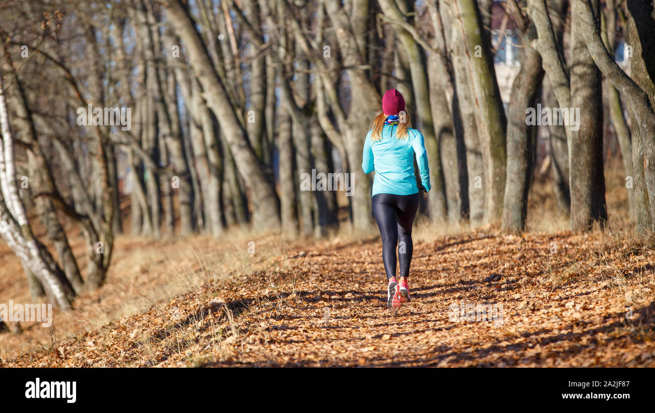 Back view of running girl in fall park in the morning. Sporty jogging ...