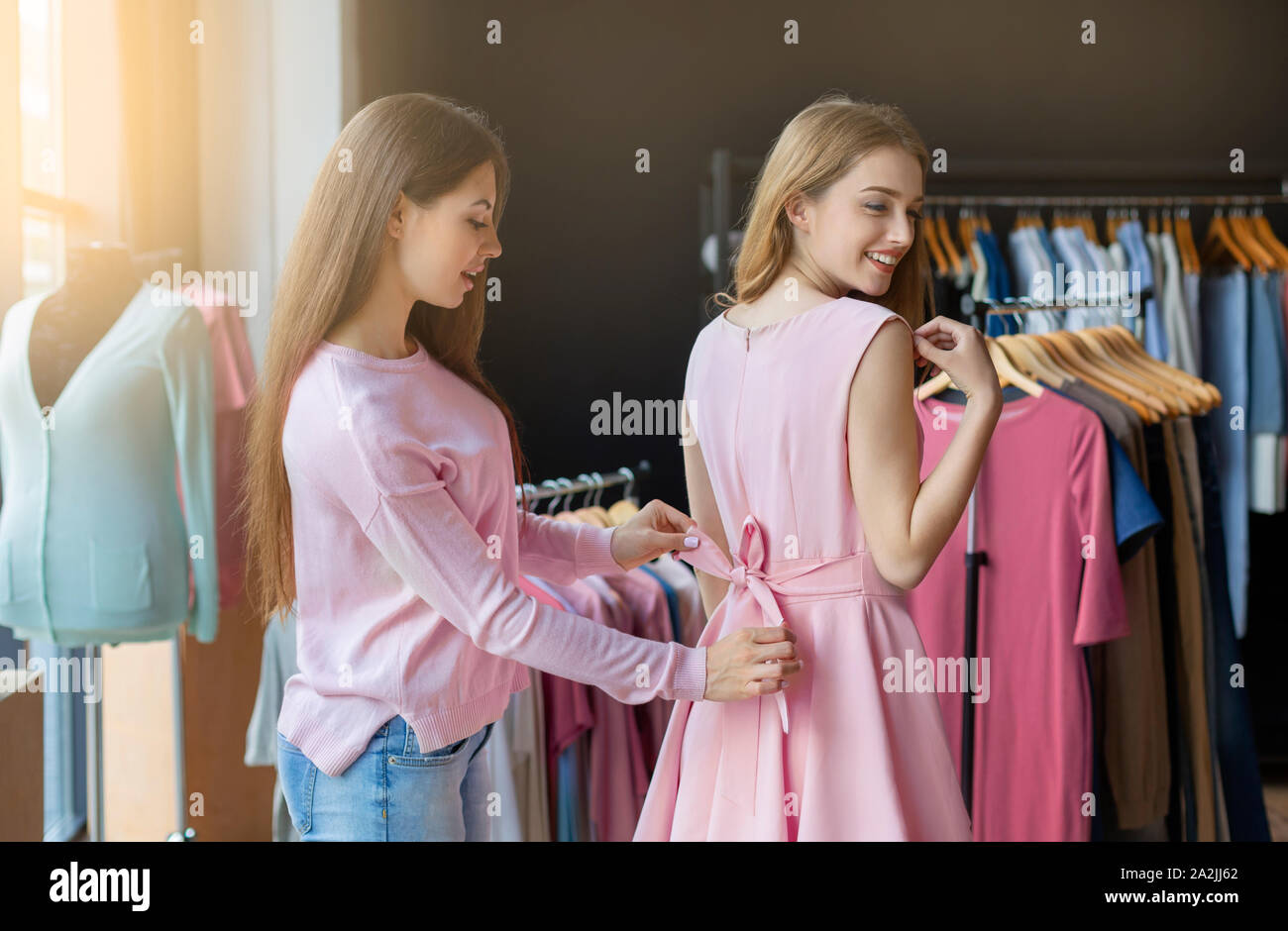 Shop assistant tightening bow on dress for pretty customer Stock Photo ...