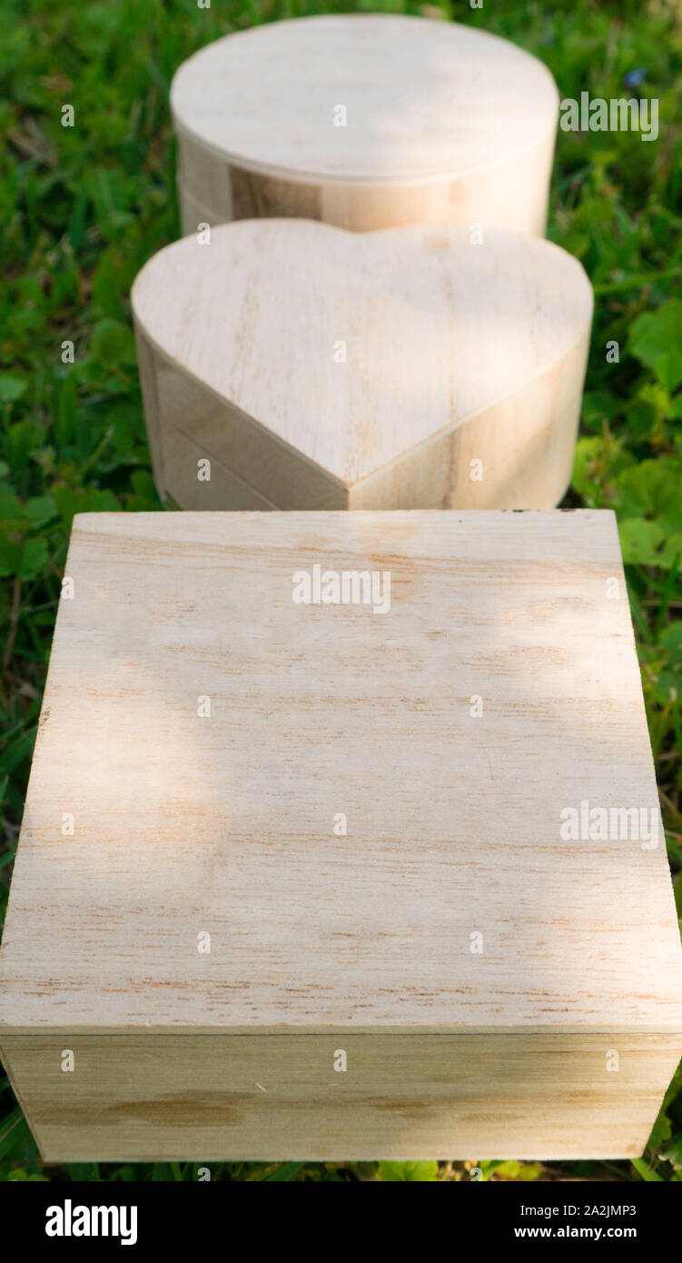 Wooden closed boxes in the shape of a cube, heart and circle on a green ...