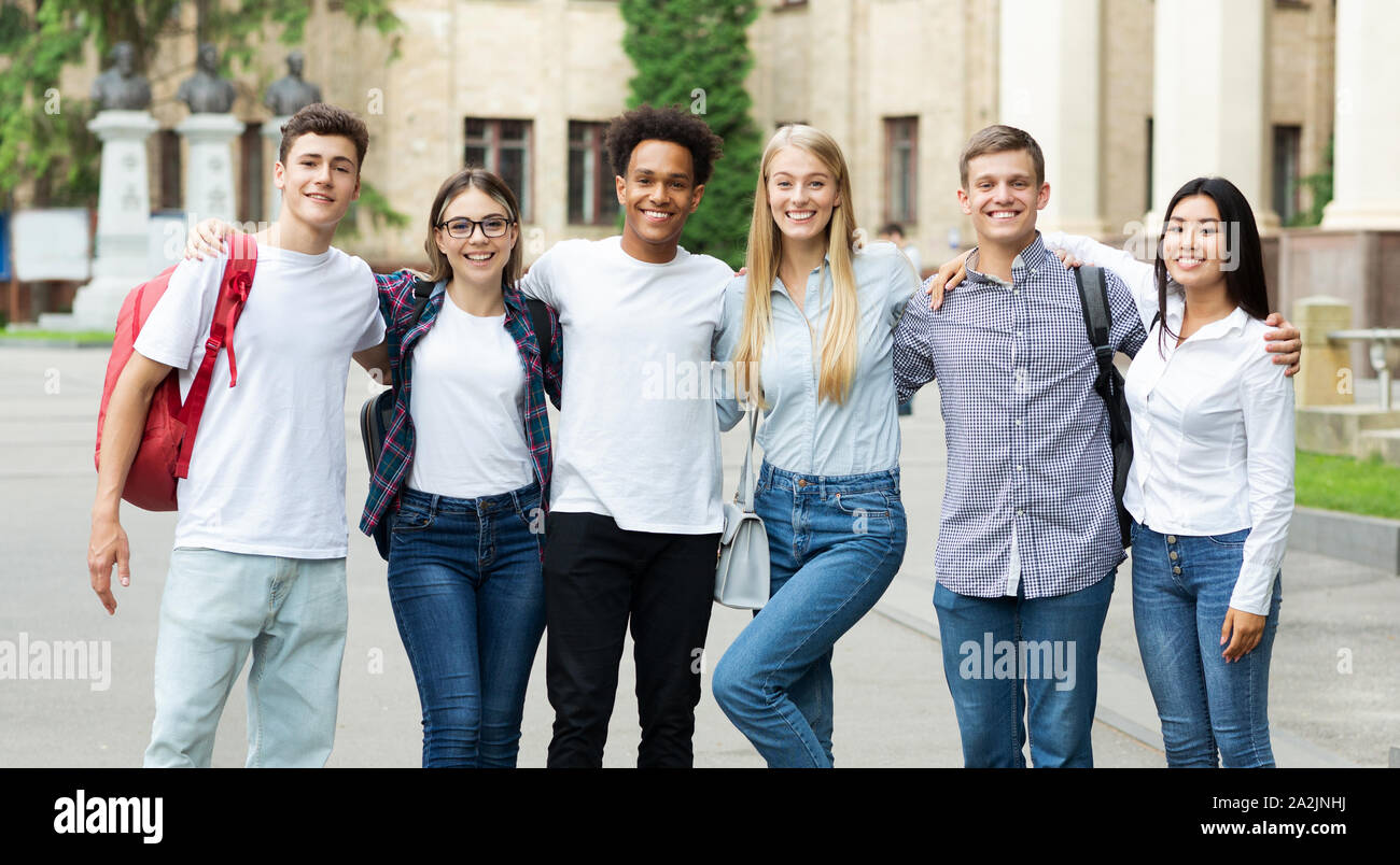 Classmates posing in front of university and smiling to camera Stock ...