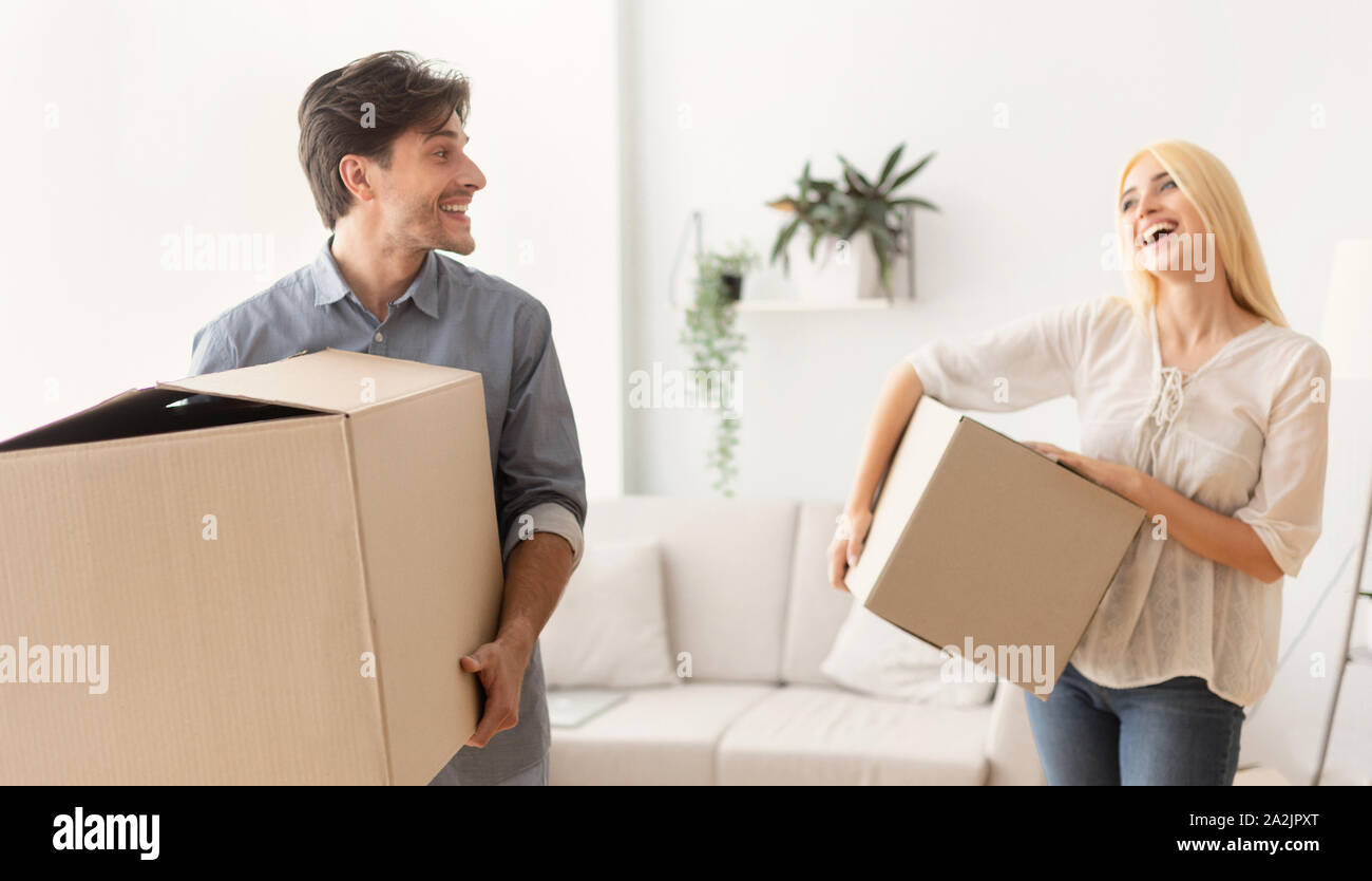 Spouses Laughing And Joking Carrying Moving Boxes In New Home Stock ...