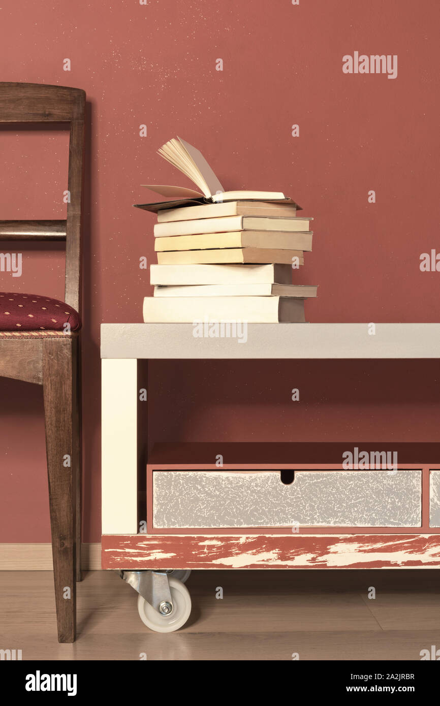 Detail of chair and stack of closed books on the console, red wall ...