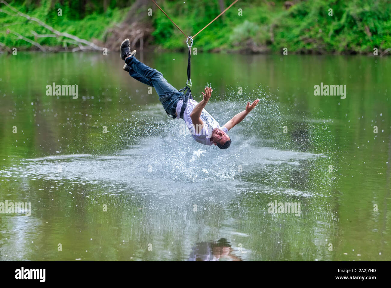 young man flying down on zipline over the river, extreme sport Stock ...