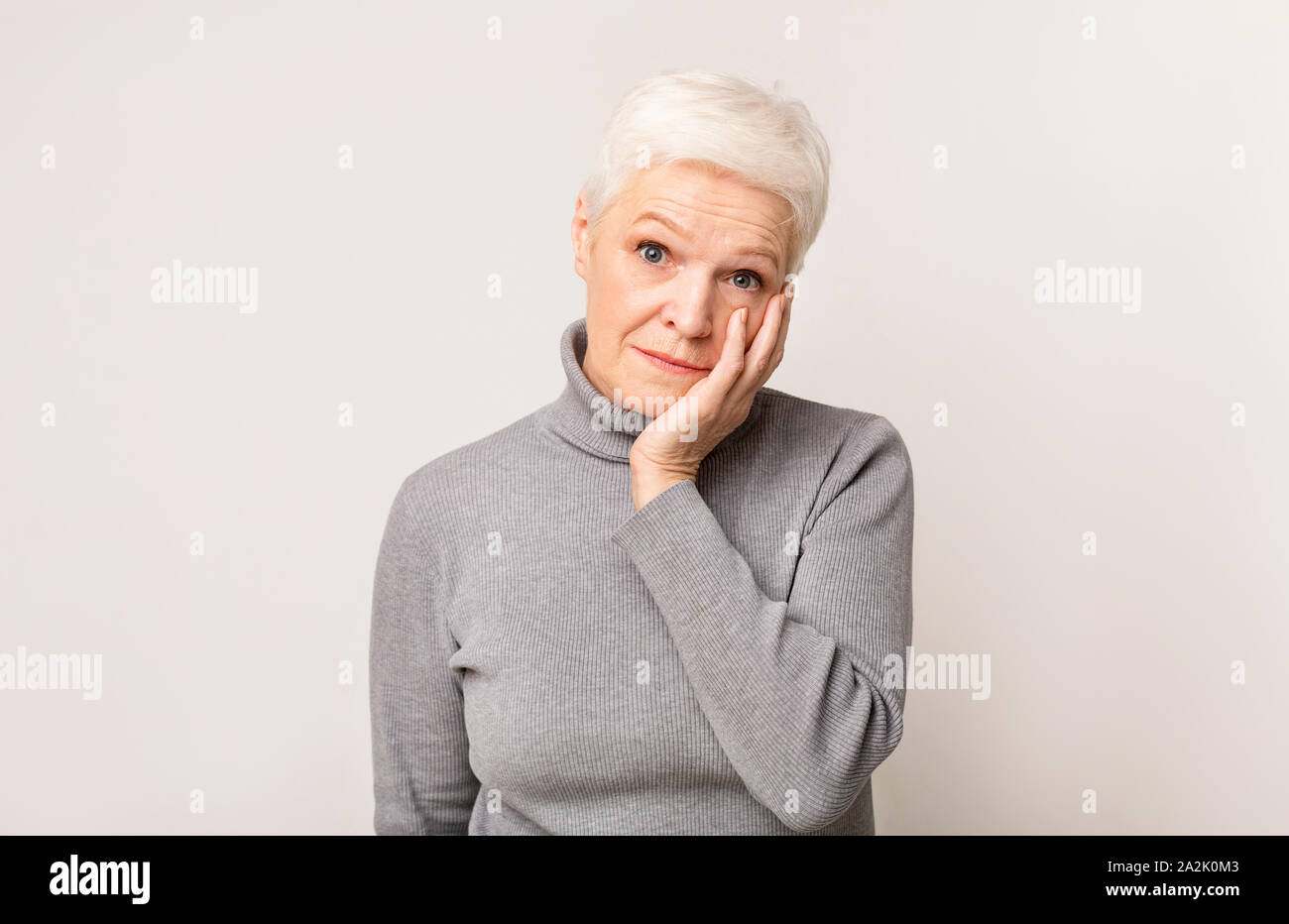 Shocked senior woman holding cheek up in total disbelief Stock Photo ...