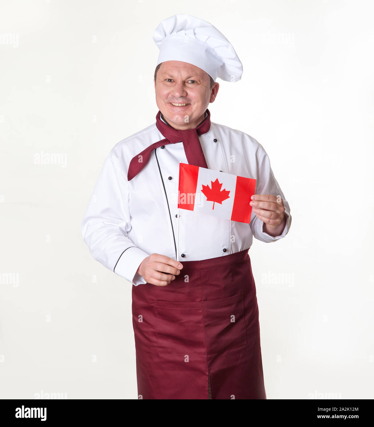 Portrait of a mature male cook with Canada flag standing on a light ...