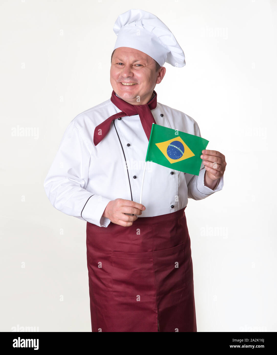 Portrait of a mature male cook with Brazil flag standing on a light ...