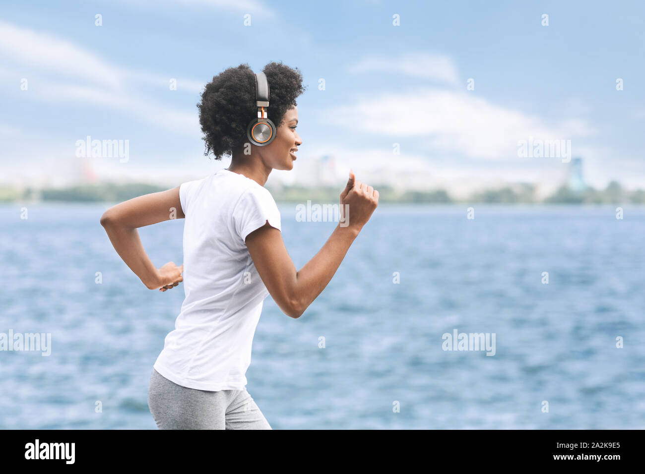 Positive Black Girl Running Outside Along River Embankment Stock Photo ...