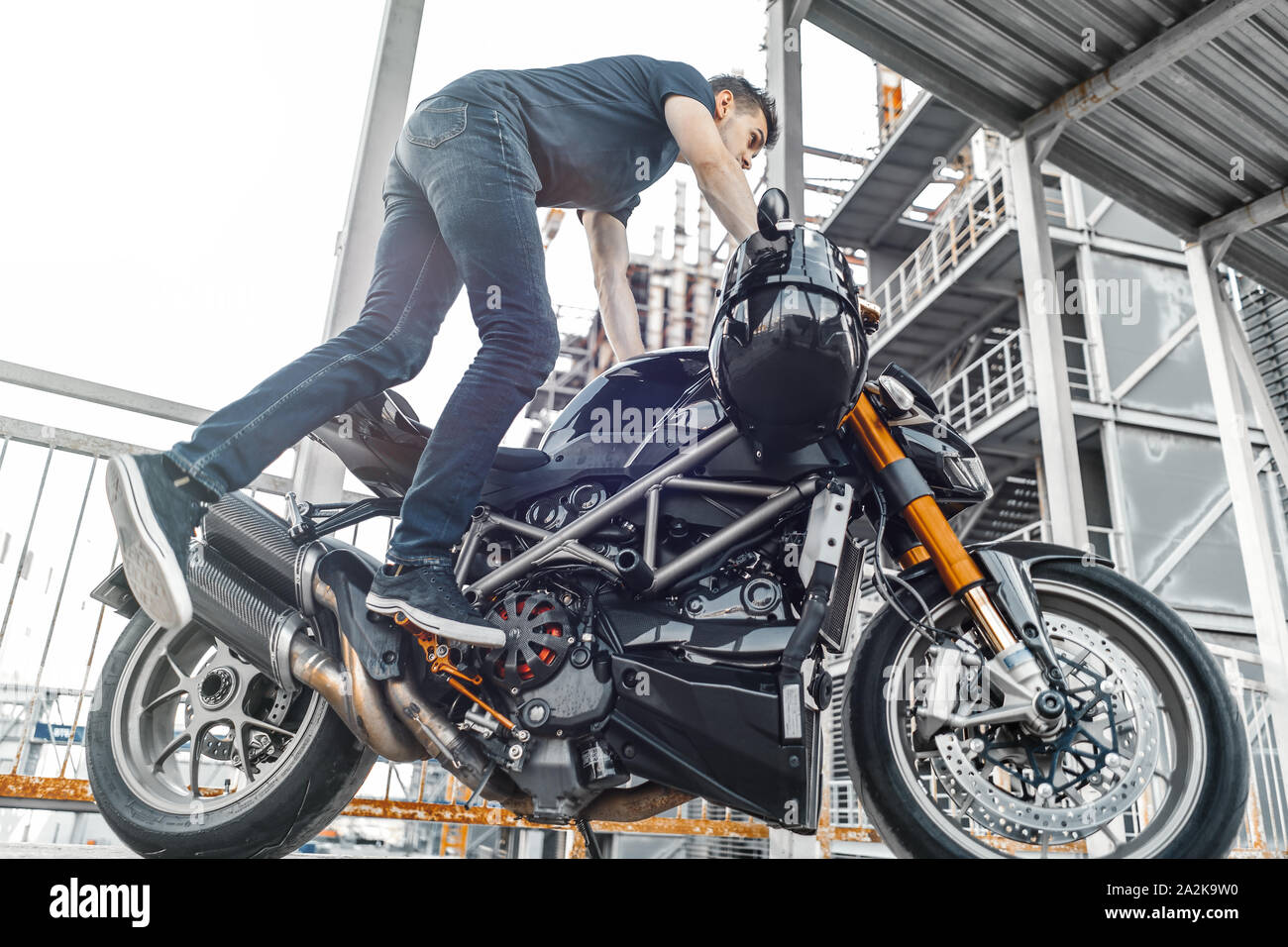 Distant plan of handsome biker sitting down on motorcycle on urban ...
