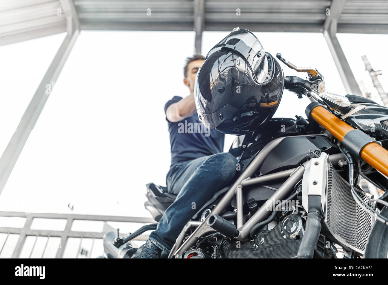 Handsome biker sitting on black motorcycle on urban background at ...