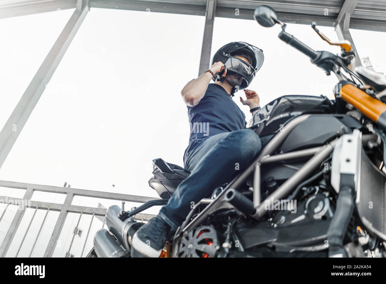 Handsome biker sitting on black motorcycle on urban background at ...
