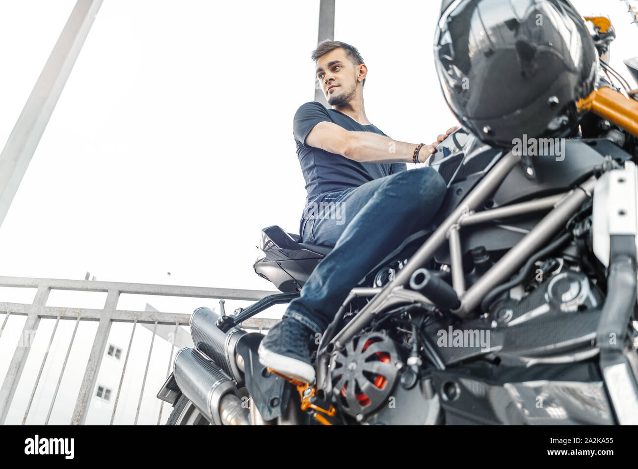 Handsome biker sitting on black motorcycle on urban background at ...