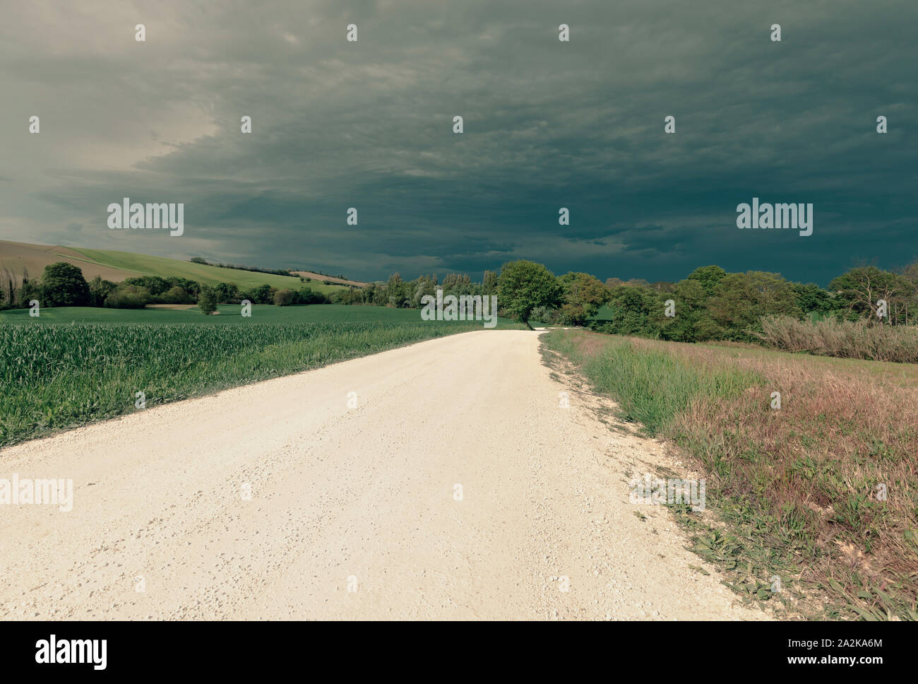 View of rural landscape in spring, white country road and dramatic sky ...