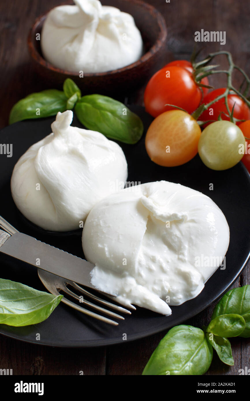Italian cheese burrata with tomatoes and herbs on a dark background ...