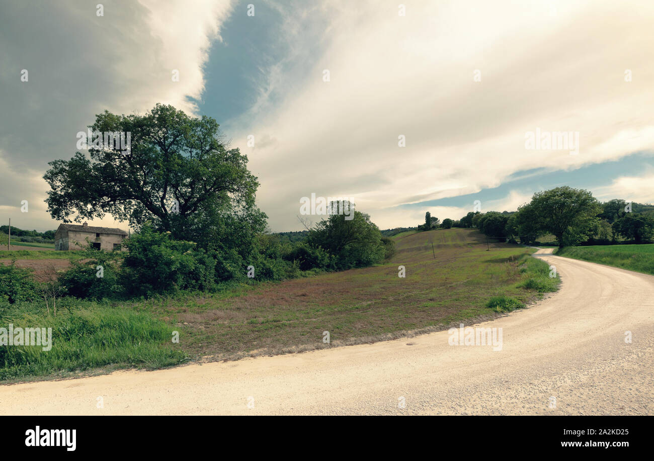 View of rural landscape in spring, white country road and dramatic sky ...