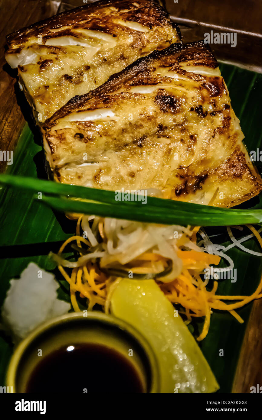 grilled cod fish with a wedge of lemon and soy sauce on the side Stock ...